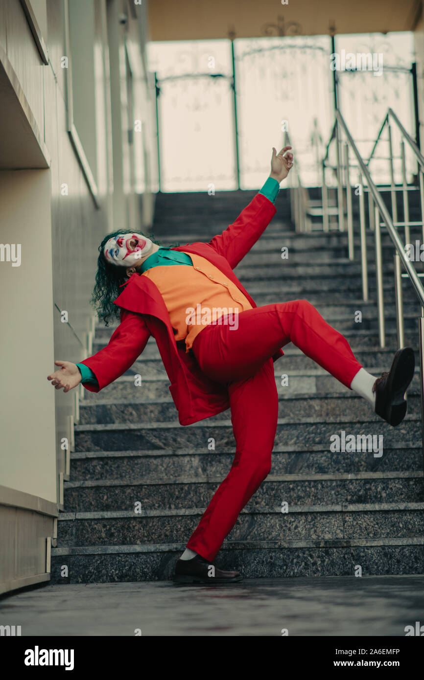 Cosplayer portrays a crazy clown against the background of the stairs ...