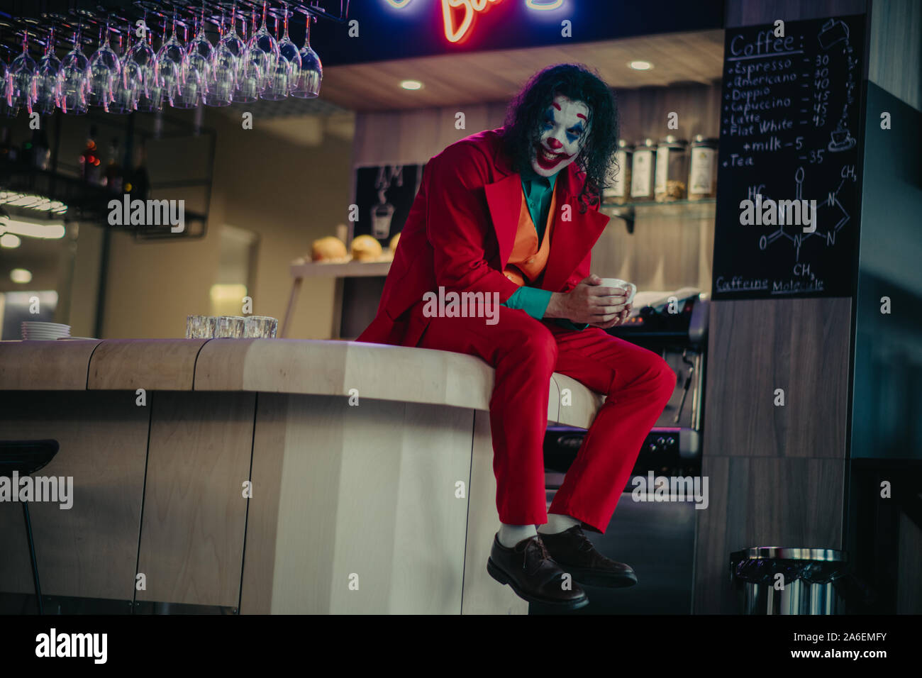 Cosplayer portrays a crazy clown and drinks coffee against the ...