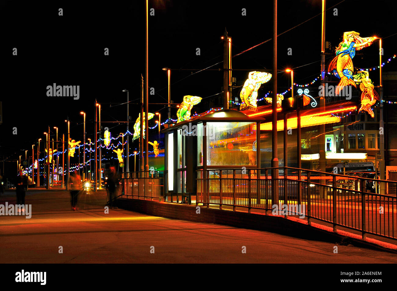 Light trails from tram passing empty shellter on the seafront during ...