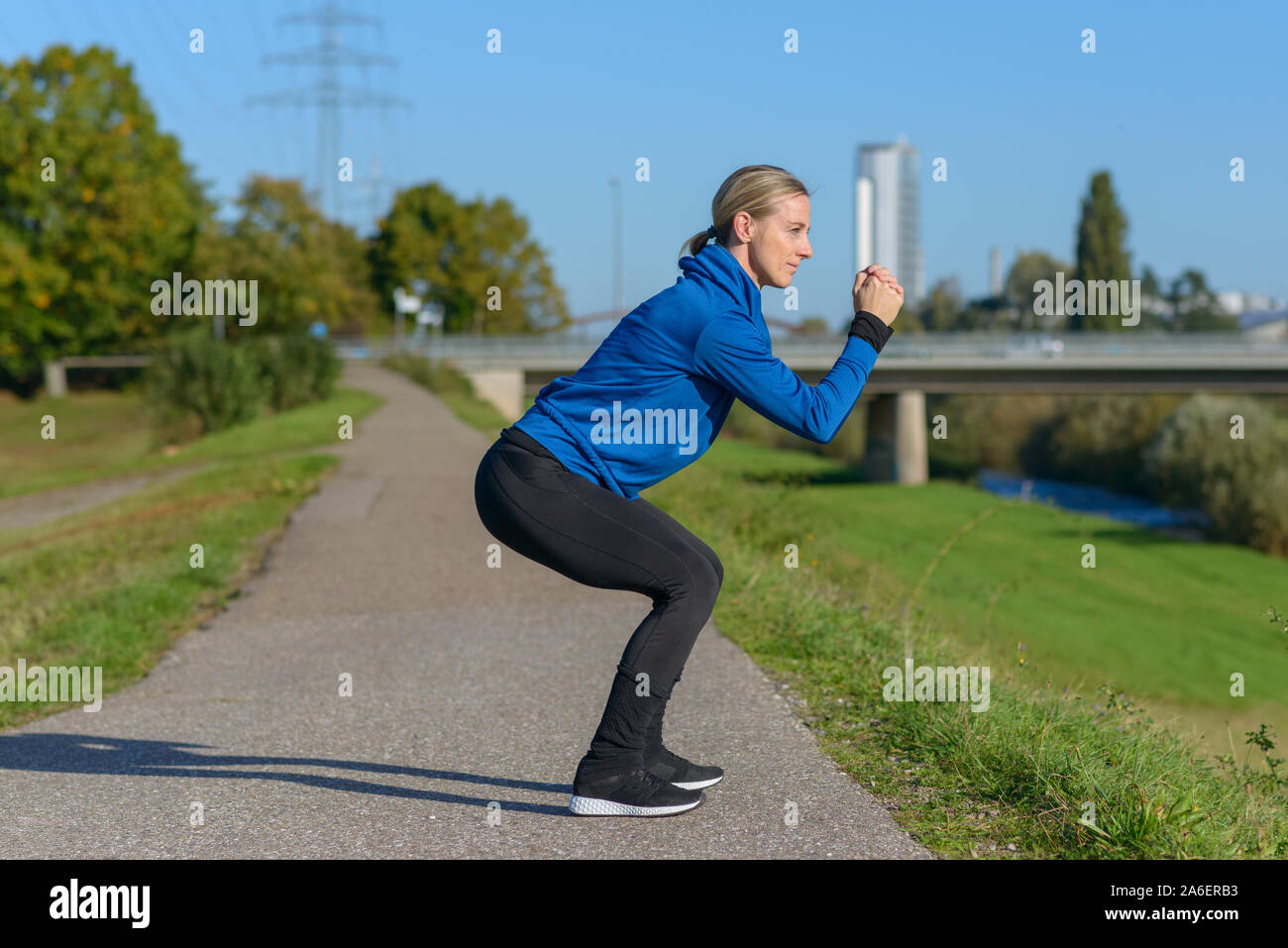Fit woman doing crouch stretches to warm up her muscles before working ...