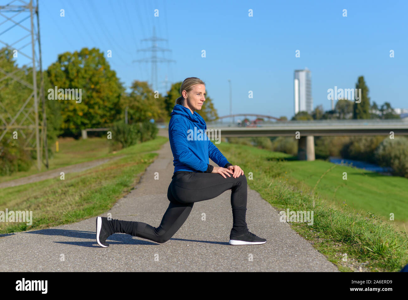 Fit athletic woman limbering up doing stretch exercises to warm up her ...