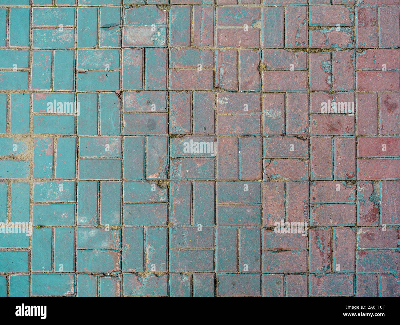 Grunge cracked red street tiles with blue paint. City street pavement ...