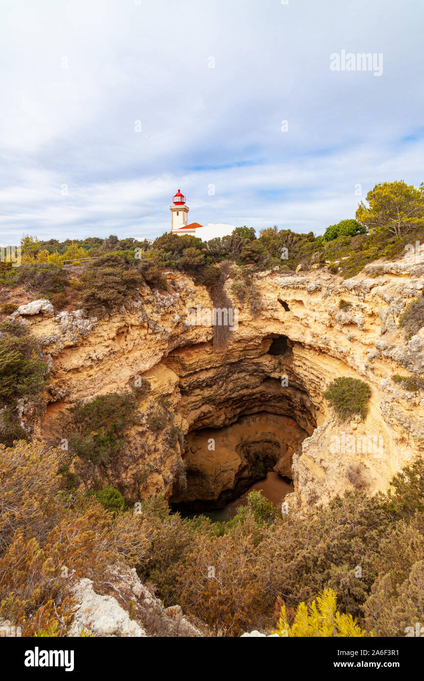 Alfanzina lighthouse above the rocky cliffs and caves on the algarve ...
