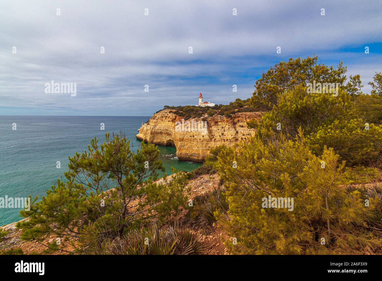 Alfanzina lighthouse above the rocky cliffs and caves on the algarve ...