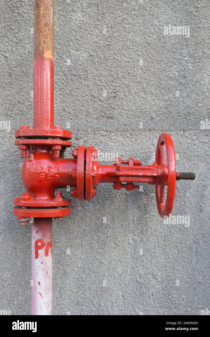 Close-up of a fire hydrant. It located on the grey wall Stock Photo - Alamy