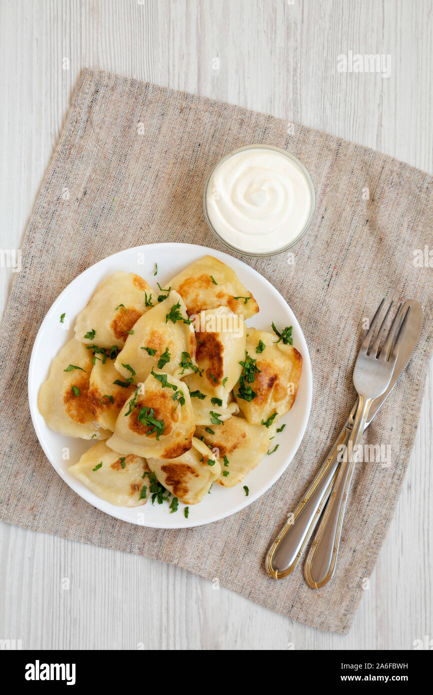 Homemade traditional polish fried potato pierohy on a white plate with ...