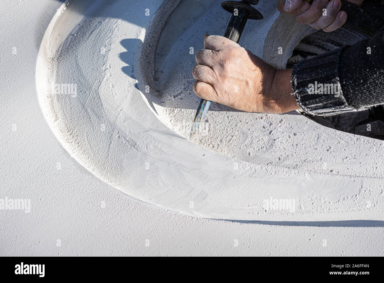 Closeup of an artist carving curves into a white stone with precise ...