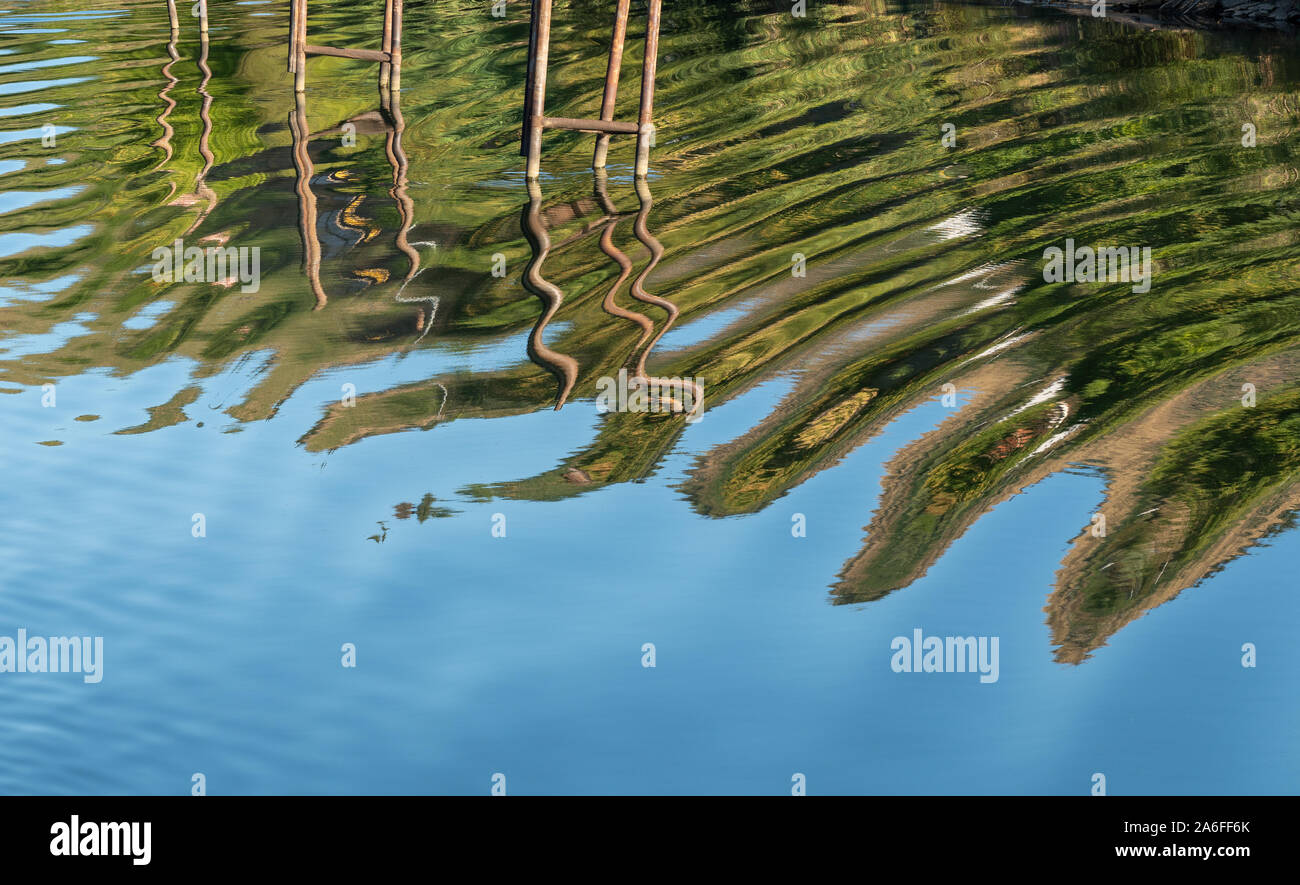 Wavy stakes and wooden poles for boat moorings and anchors reflected in ...