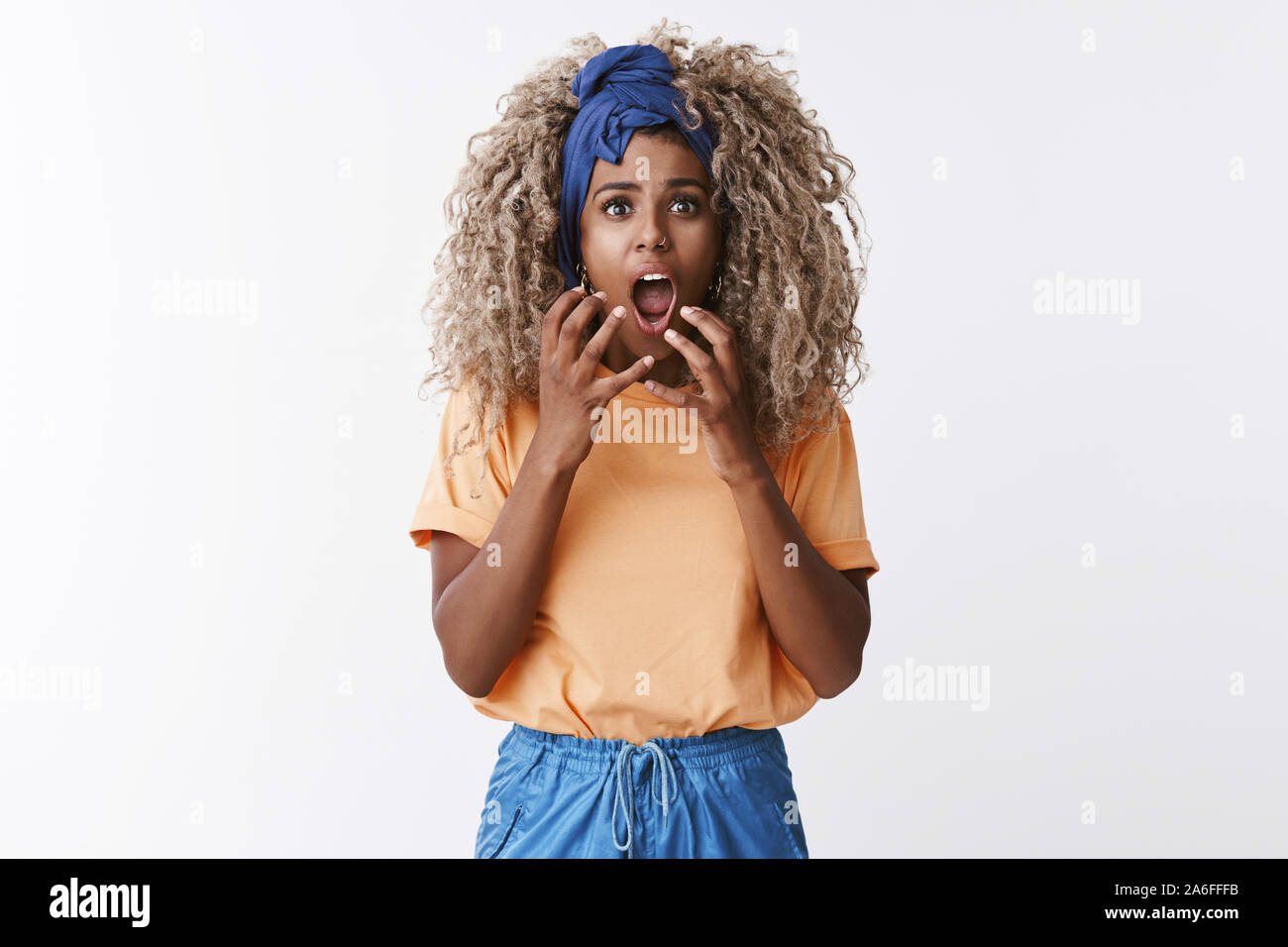 Shocked stupified african-american blond curly woman in stylish outfit ...