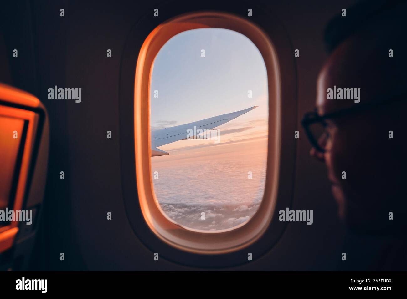 Man looking throught vindow of airplane during flight above clouds at ...