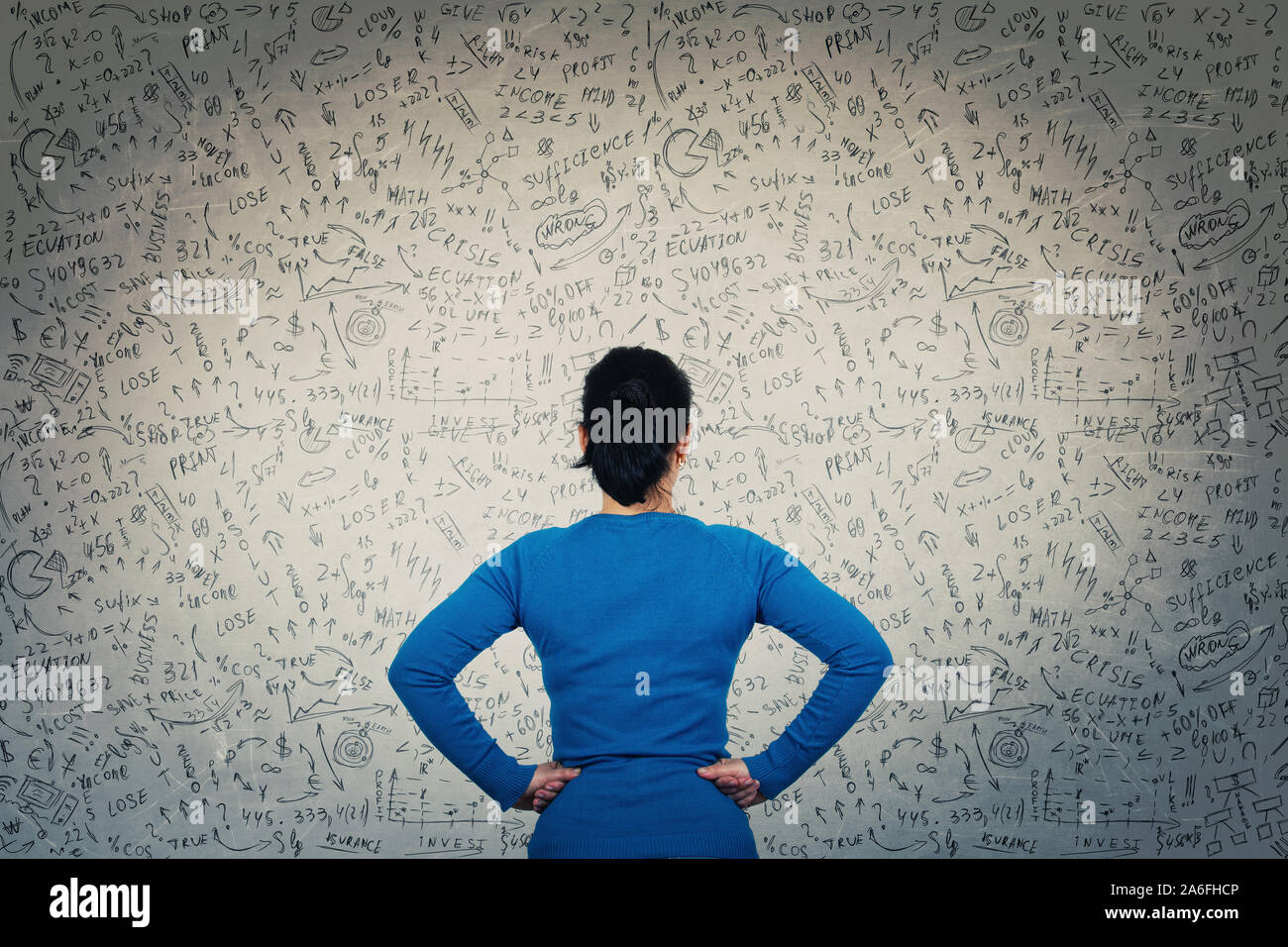 Rear view of a puzzled woman in front of a wall, hands on hips, try to ...