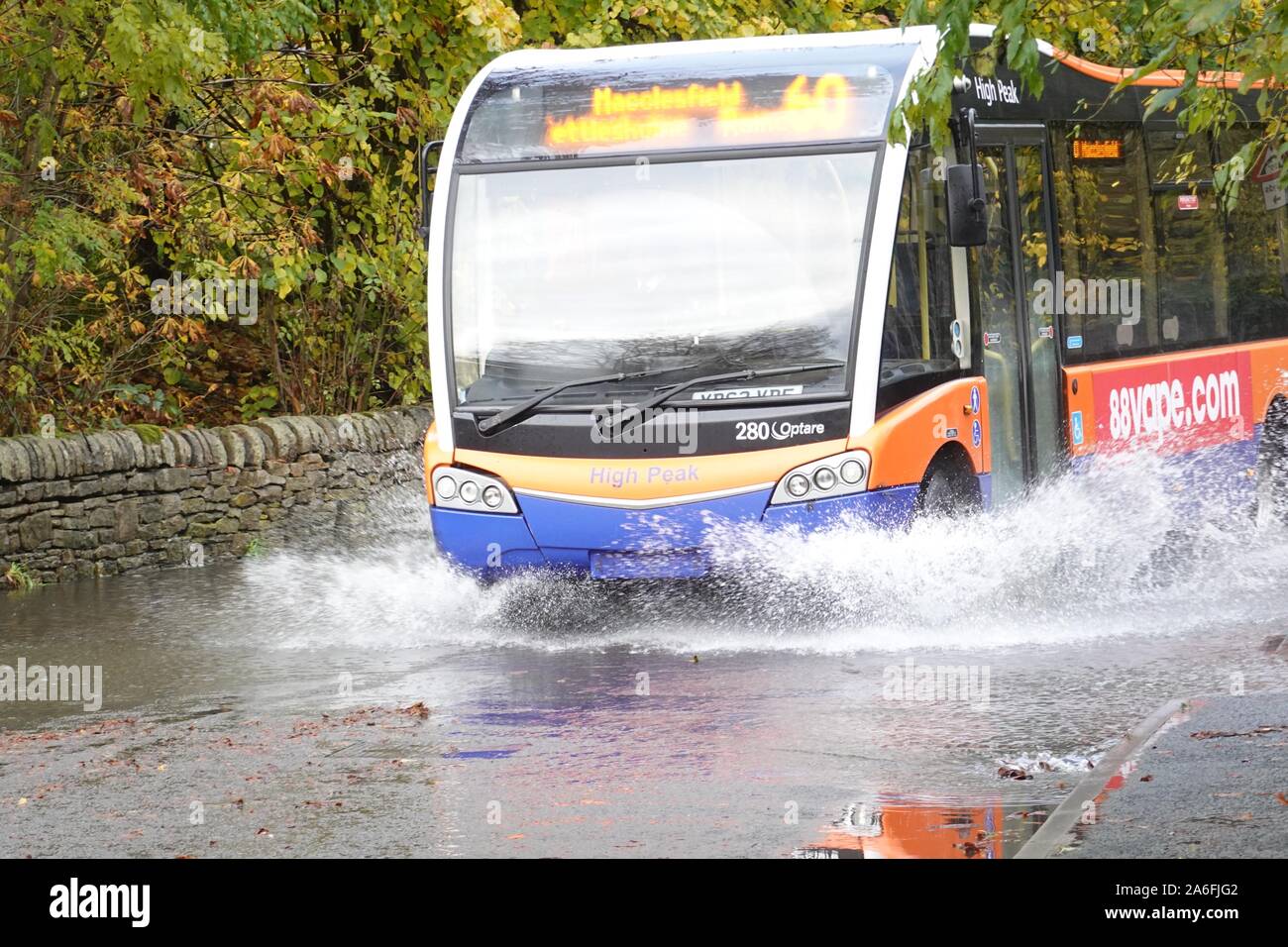 A bus goes through water on a flooded road in New Mills, Derbyshire ...