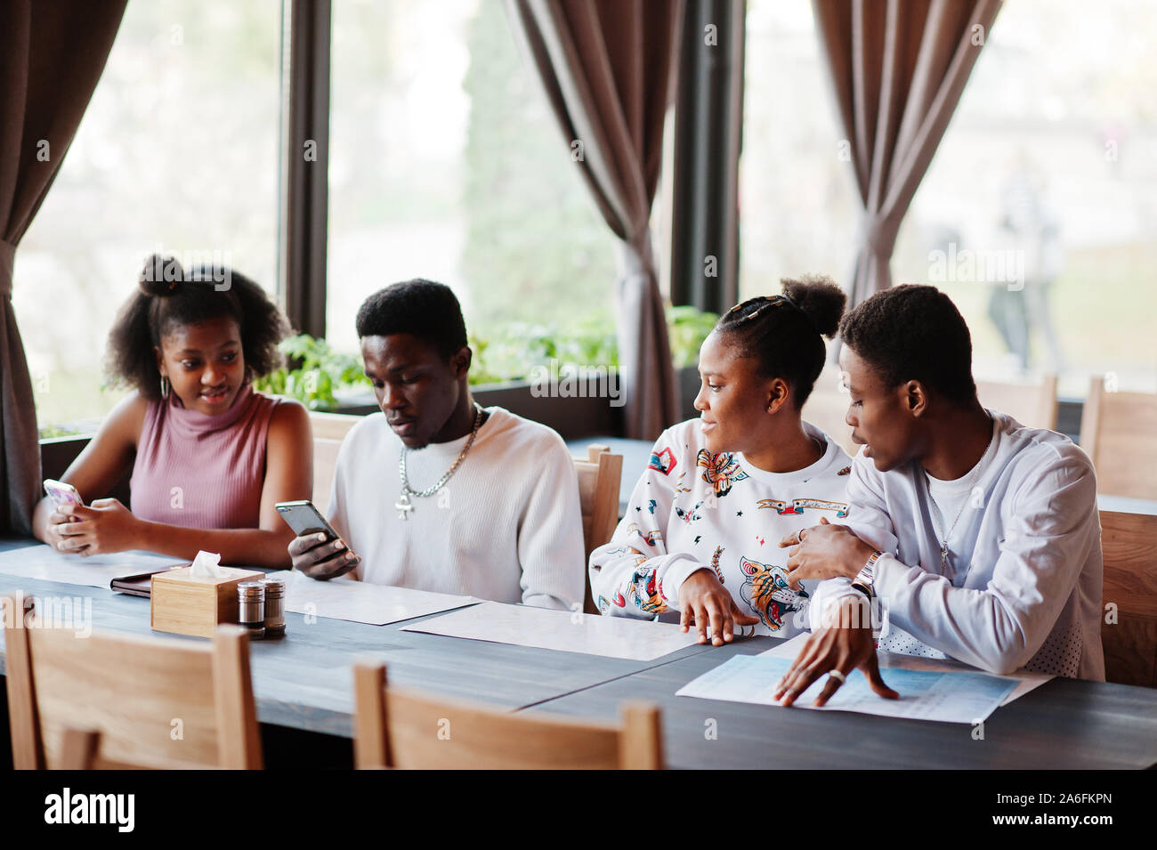 Happy african friends sitting and chatting in cafe. Group of black ...