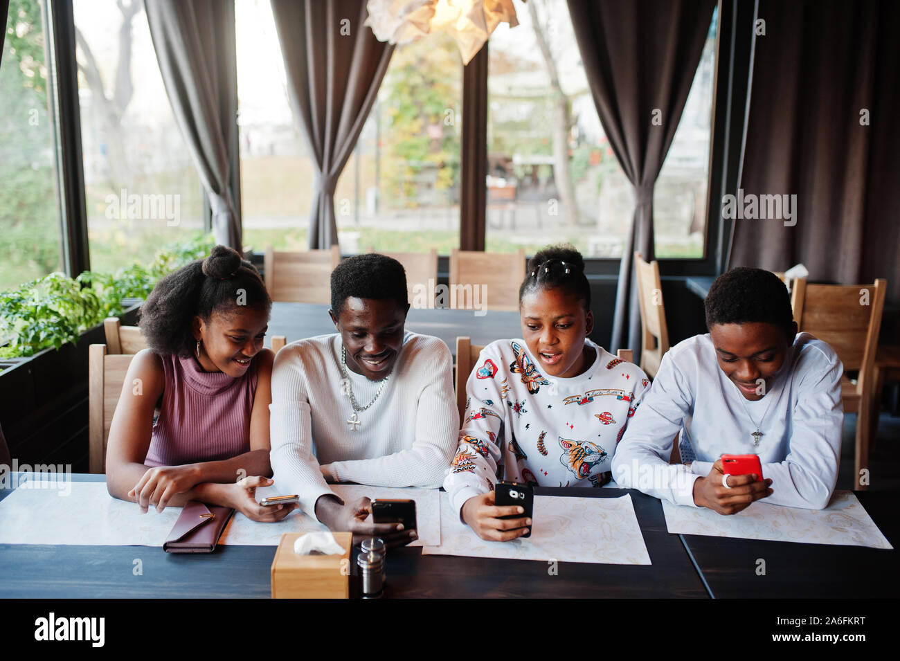 Happy african friends sitting and chatting in cafe. Group of black ...