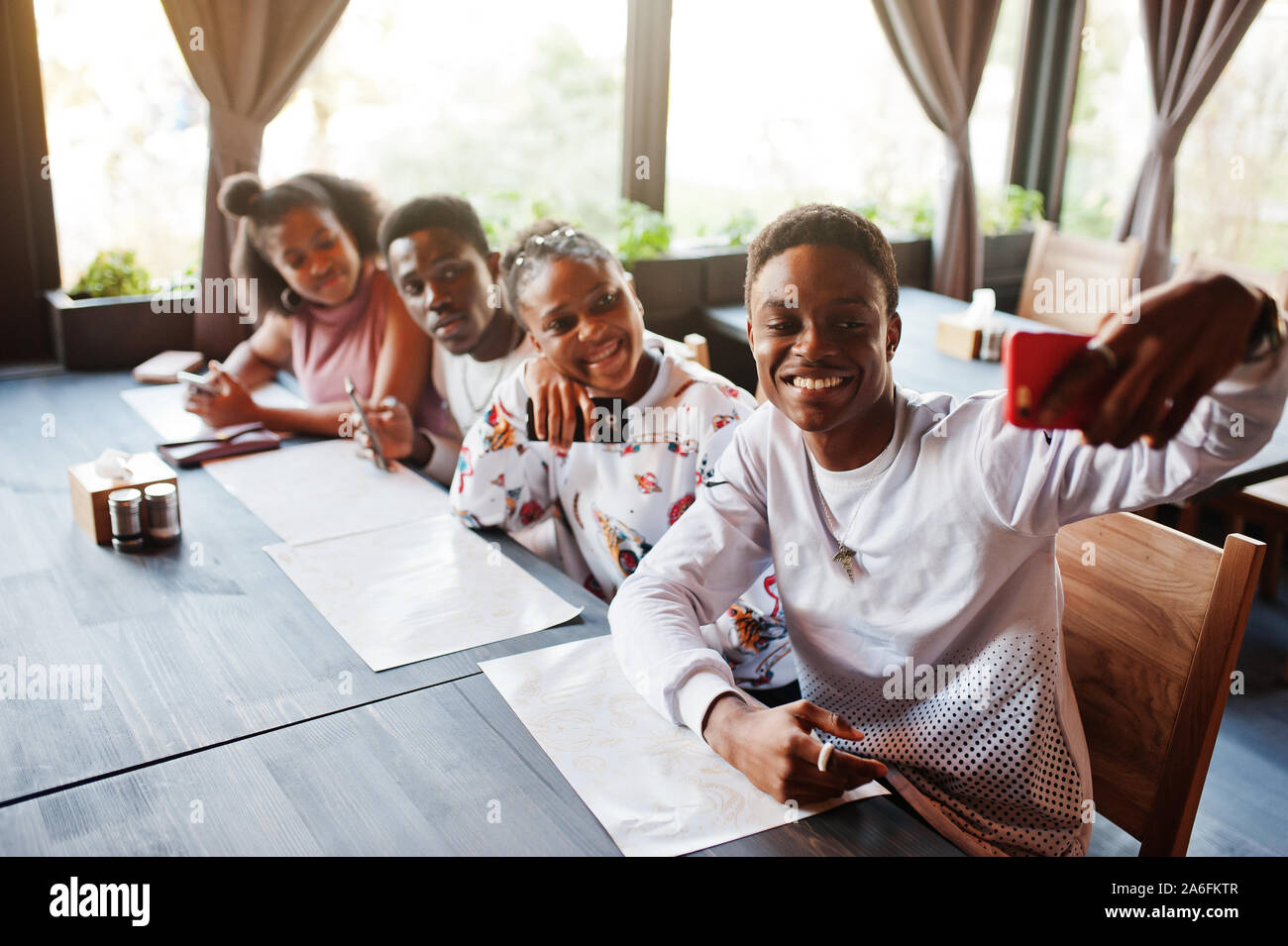 Happy african friends sitting and chatting in cafe. Group of black ...