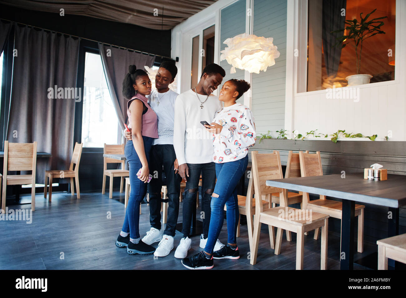 Happy african friends standing and chatting in cafe. Group of black ...