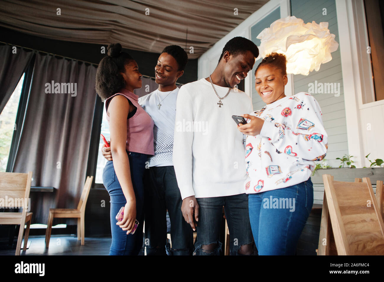 Happy african friends standing and chatting in cafe. Group of black ...