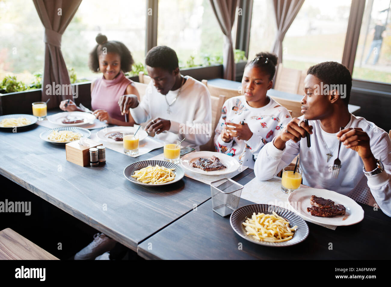 Happy african friends sitting, chatting in cafe and eat food. Group of ...