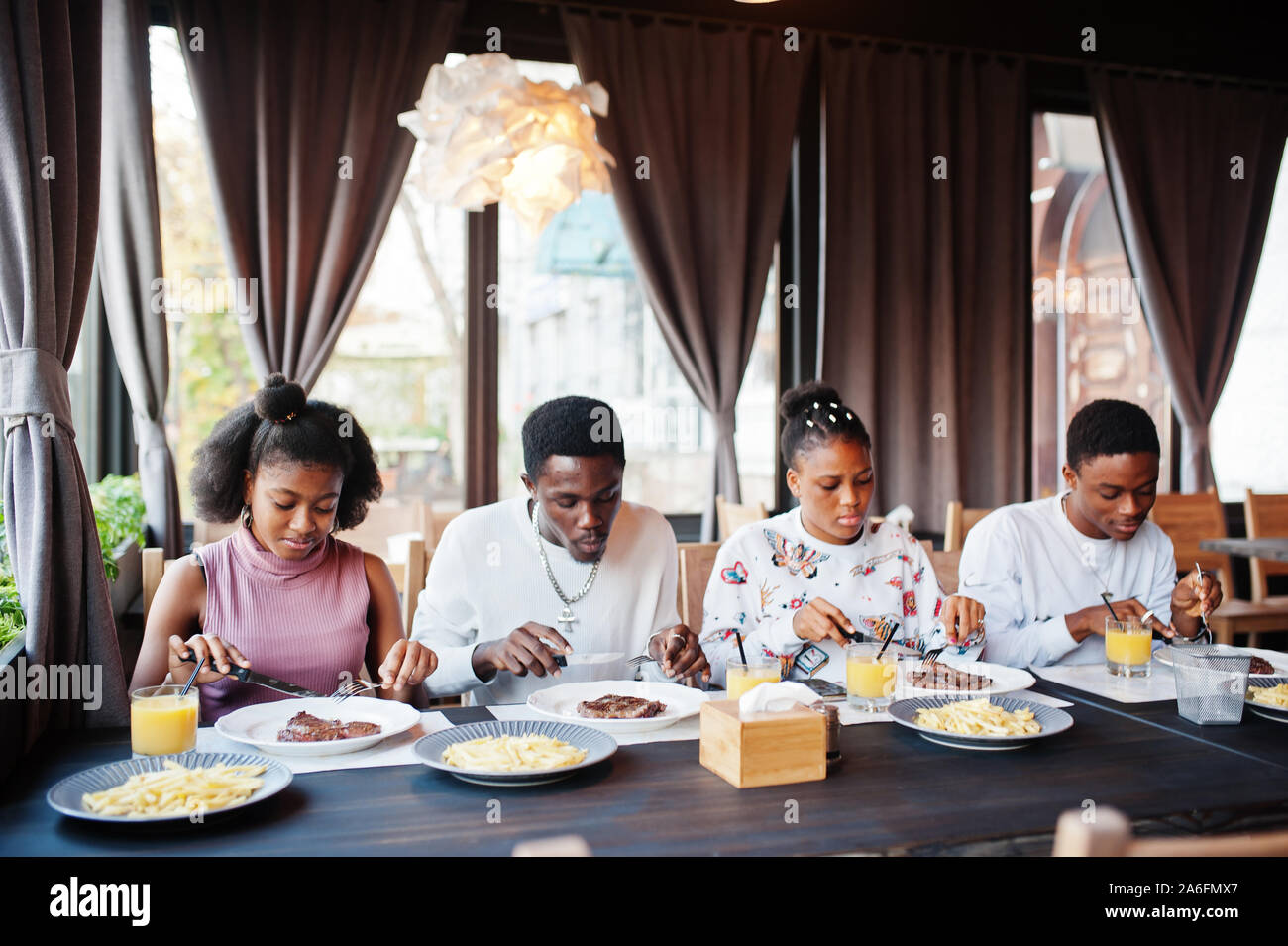 Happy african friends sitting, chatting in cafe and eat food. Group of ...