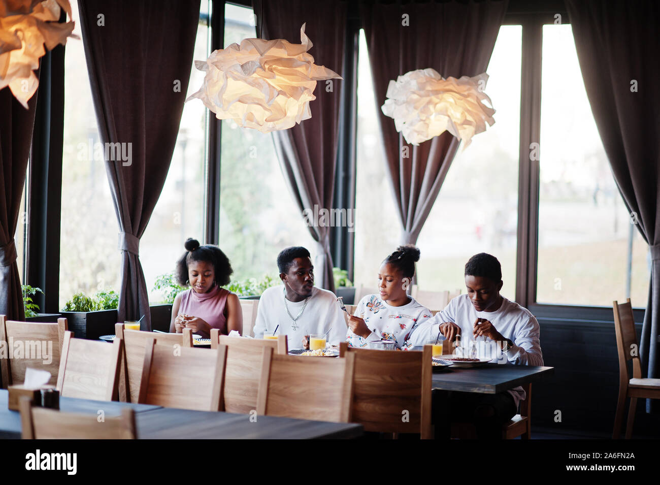 Happy african friends sitting, chatting in cafe and eat food. Group of ...
