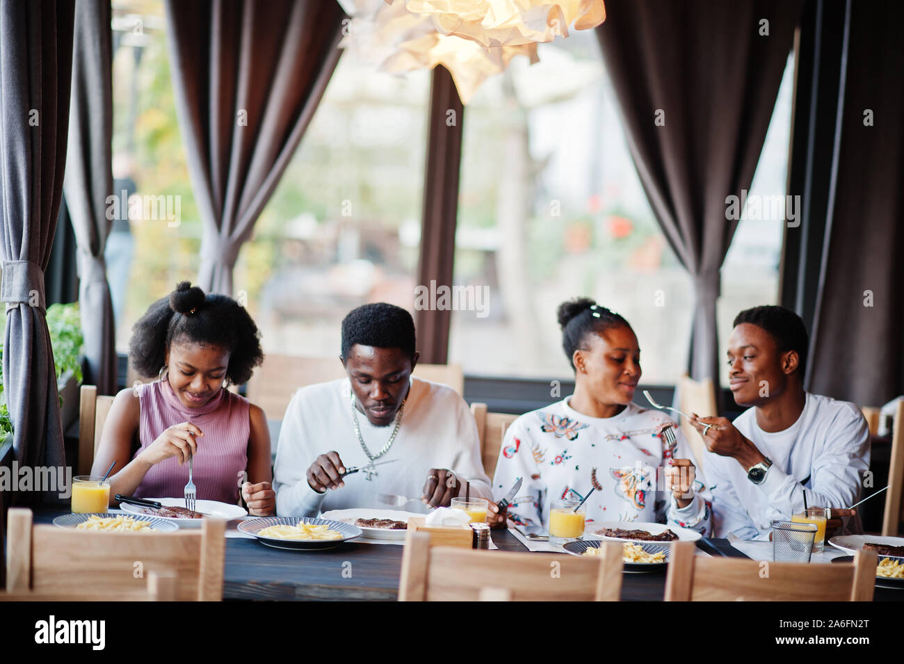 Happy african friends sitting, chatting in cafe and eat food. Group of ...