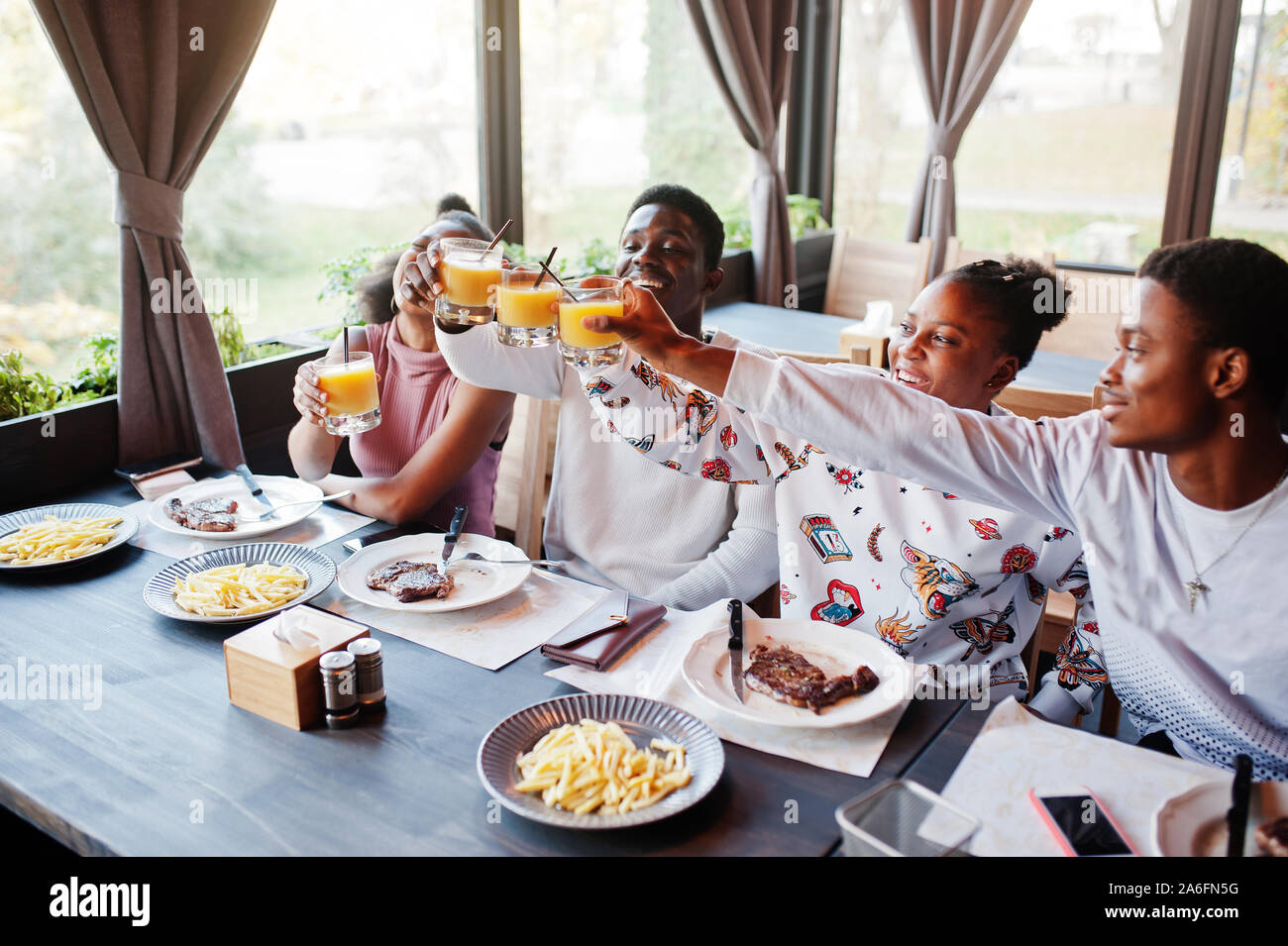 Happy african friends sitting, chatting in cafe and eat food. Group of ...