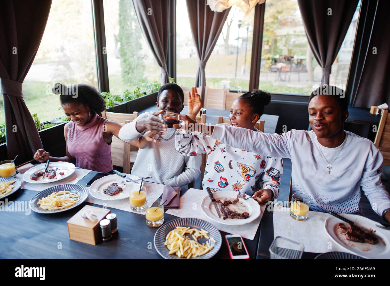 Happy african friends sitting, chatting in cafe and eat food. Group of ...