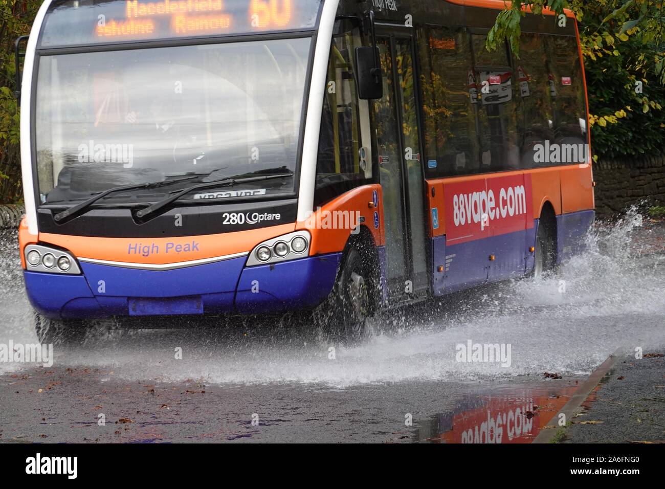 A bus goes through water on a flooded road in New Mills, Derbyshire ...