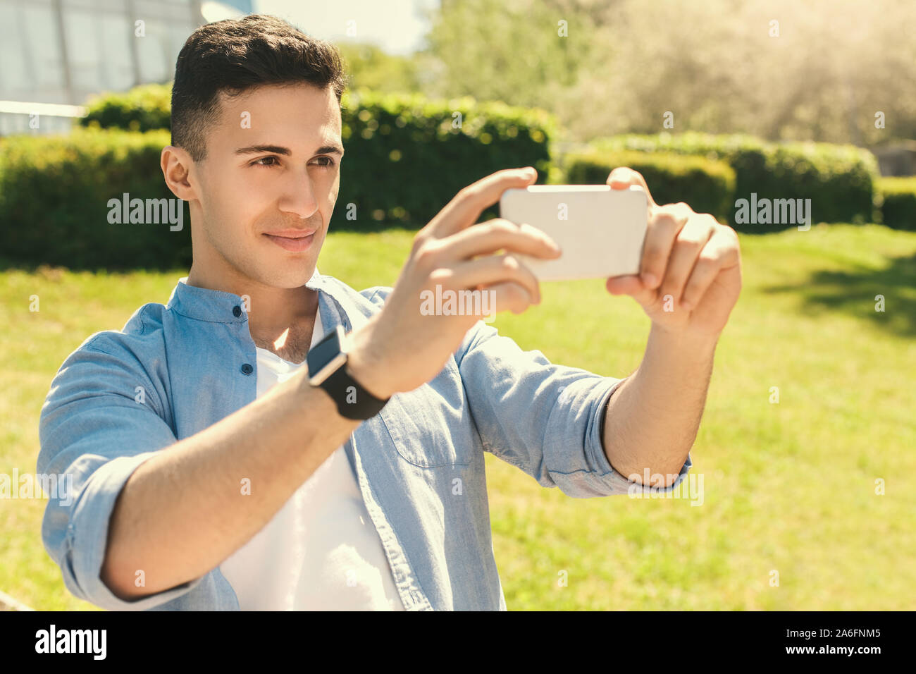 Outdoors Leisure. Stylish guy wearing watch standing in park taking ...