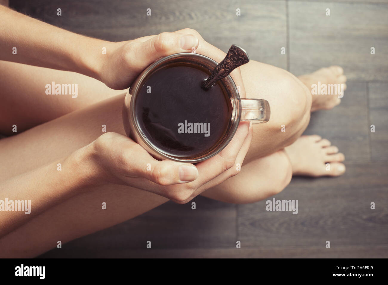 unrecognizable young woman with cup of hot tea, closeup hands and bare ...