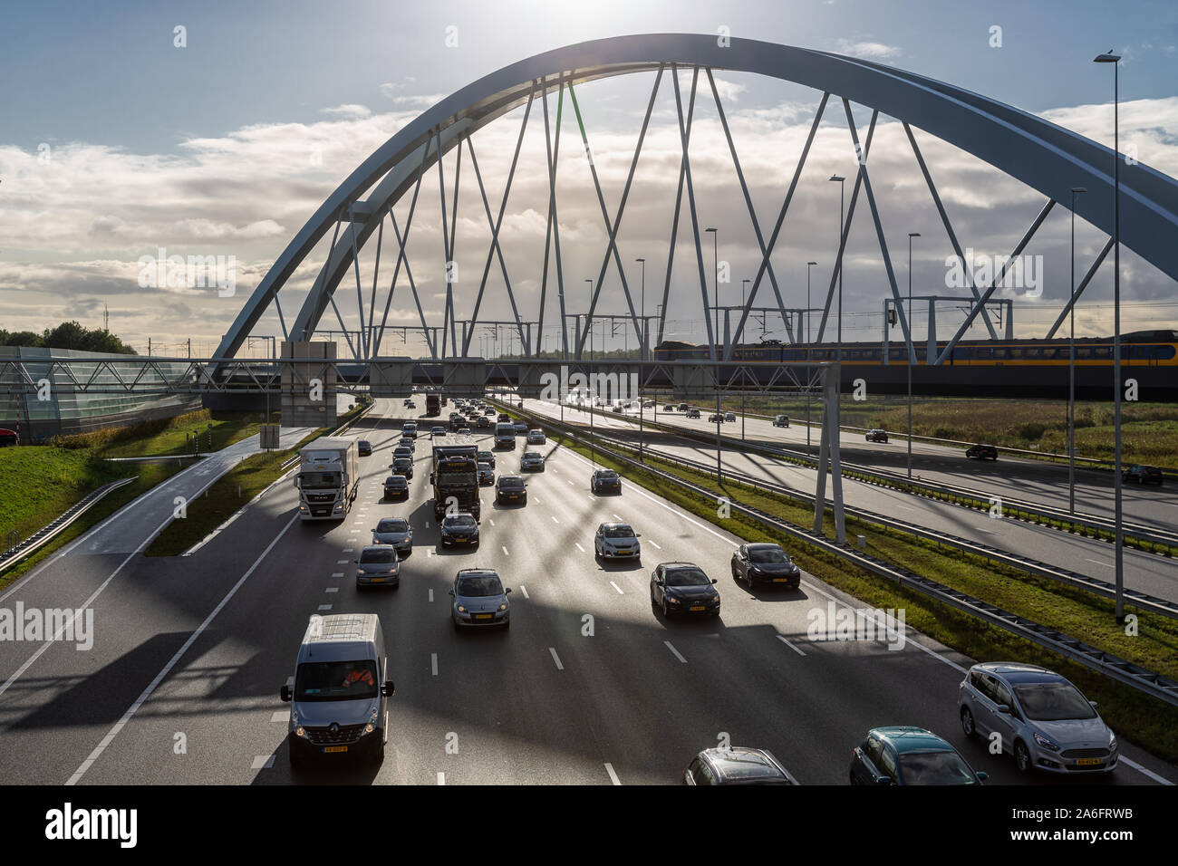 Dutch motorway near Amsterdam with railway bridge and passing train ...