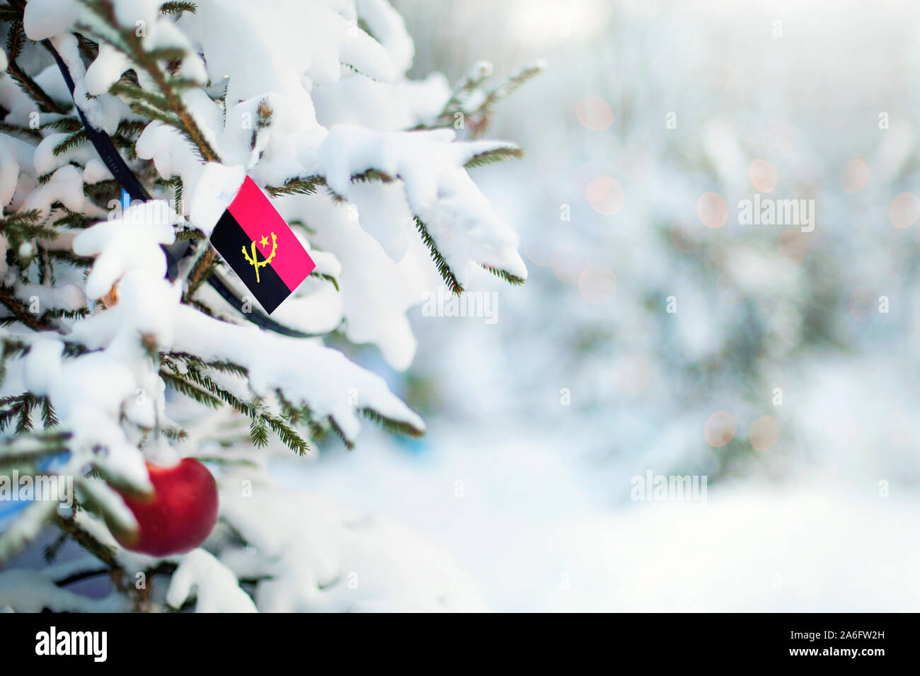 Christmas Angola. Xmas tree covered with snow, decorations and a flag ...