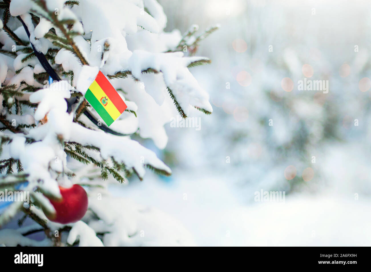 Christmas Bolivia. Xmas tree covered with snow, decorations and a flag ...