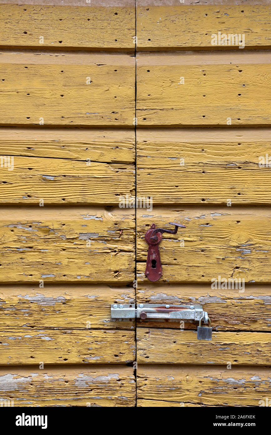 Old wooden doors with flacking paint, slide bolt and keyhole for lock ...