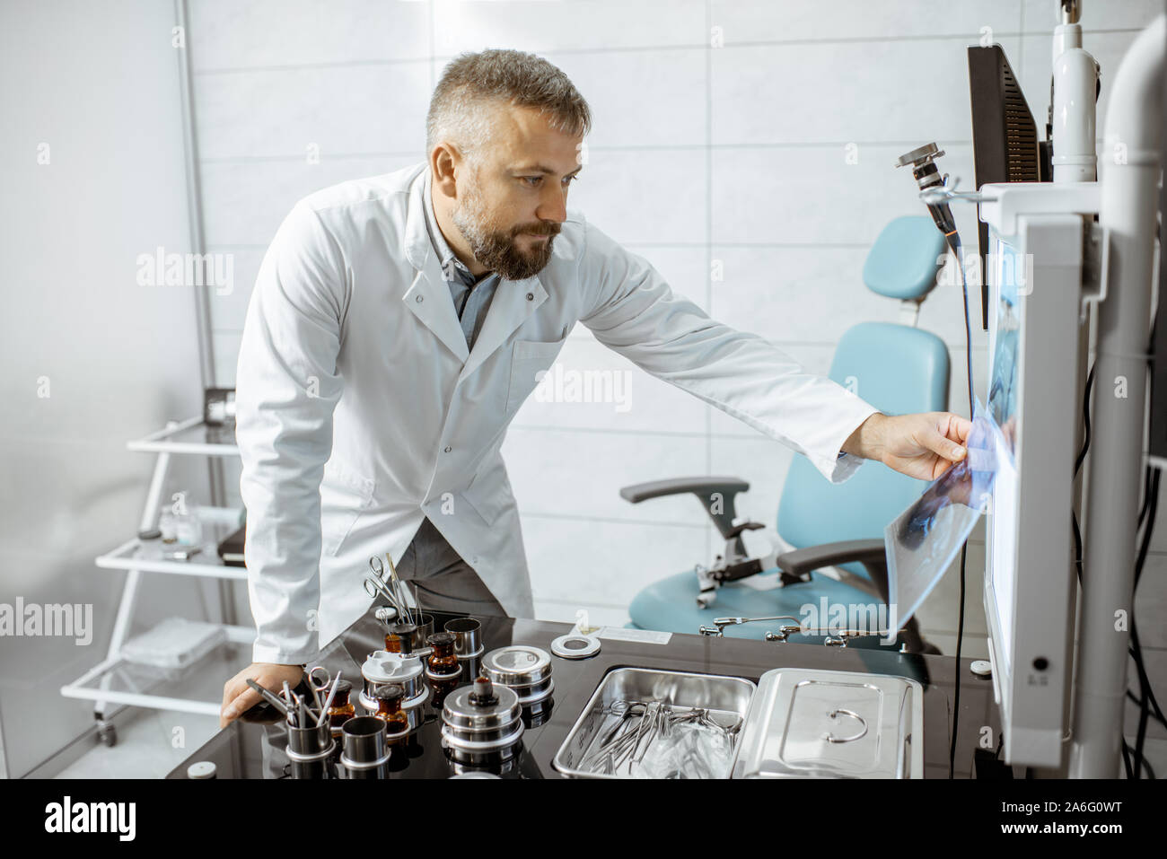 Senior otolaryngologist working in ENT office, examining CT picture of ...