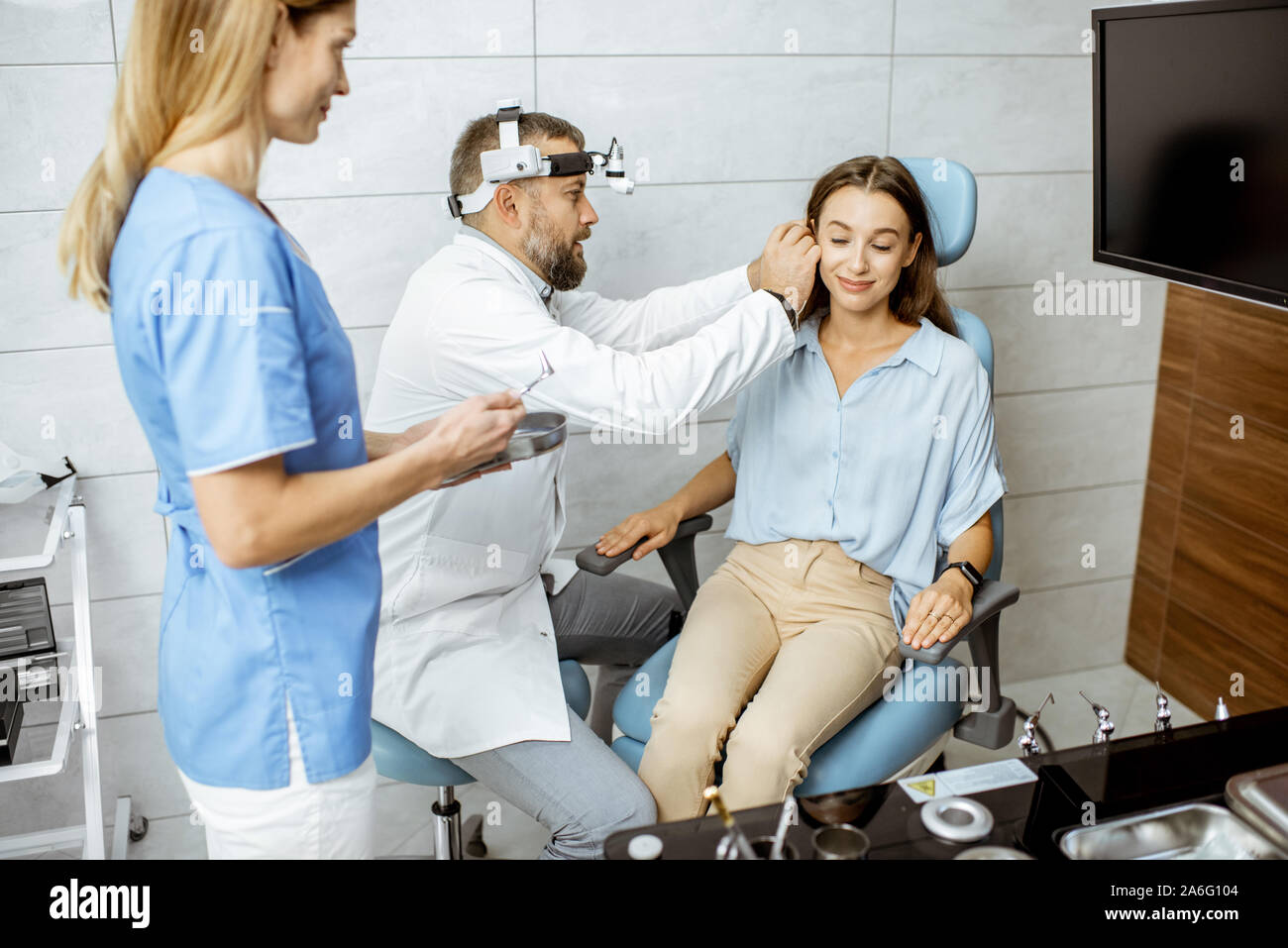 Senior otolaryngologist examining ear of a young patient with female ...