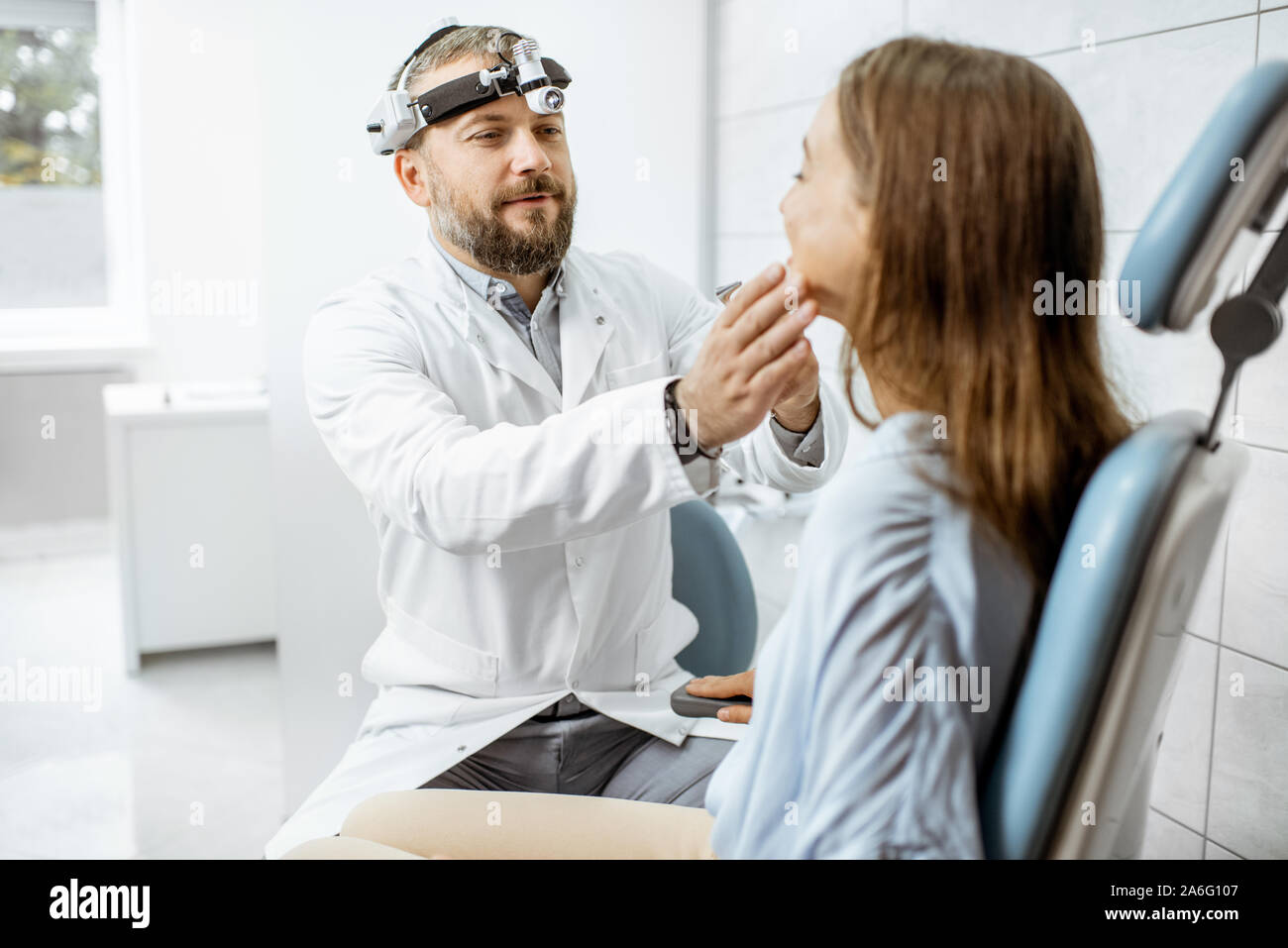 Senior otolaryngologist examining nose of a young patient during a ...