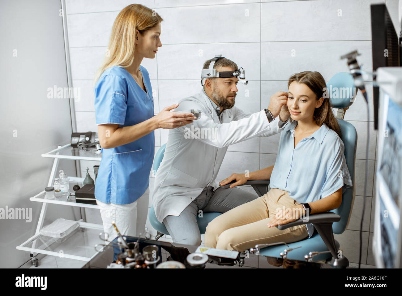Senior otolaryngologist examining ear of a young patient with female ...