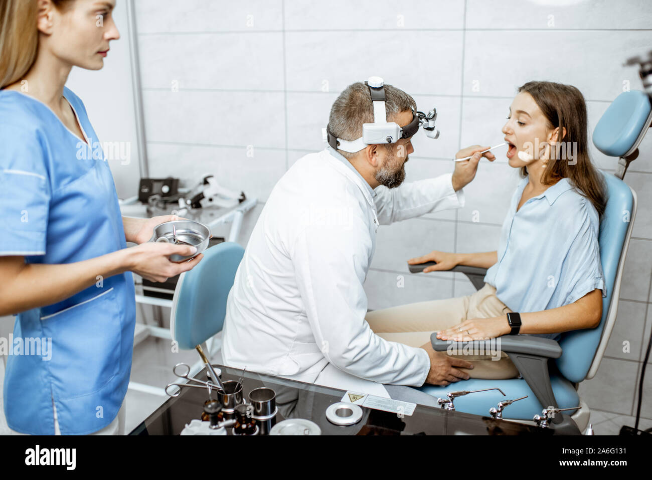 Patient with senior otolaryngologist and assistant in ENT office during ...