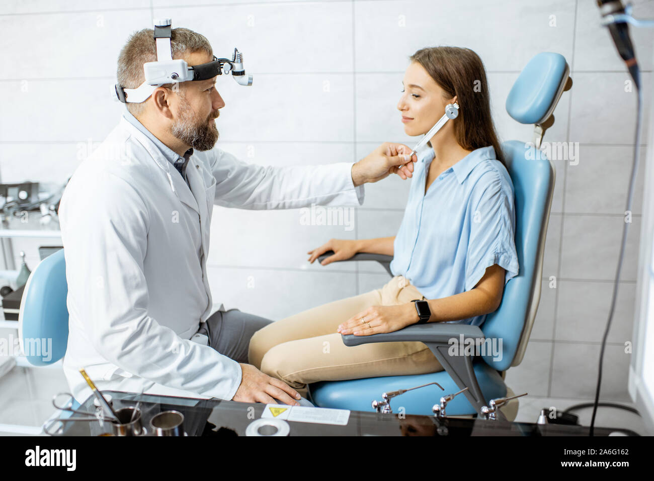 Senior otolaryngologist examining ears with ENT tuning fork for a young ...