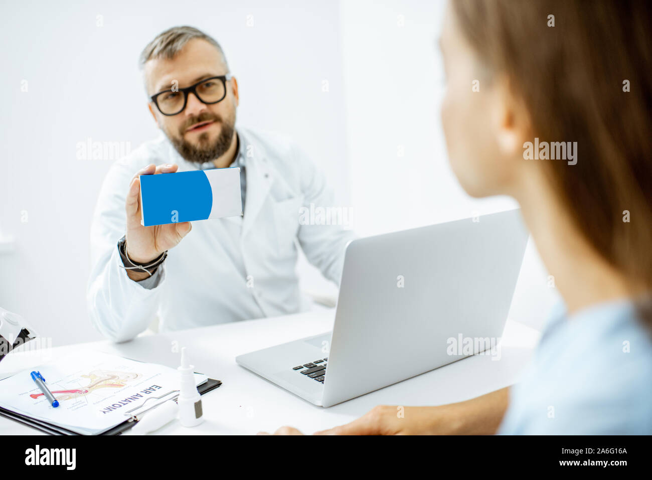 Senior doctor offering some medicine for a young patient, holding box ...