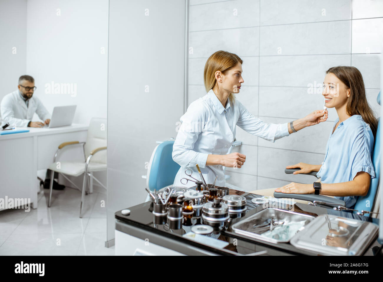 Female otolaryngologist examining ears with ENT tuning fork for a young ...