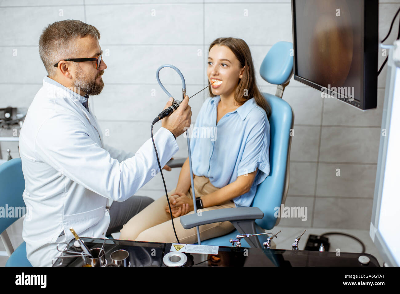 Senior otolaryngologist making endoscopic examination of an oral cavity ...