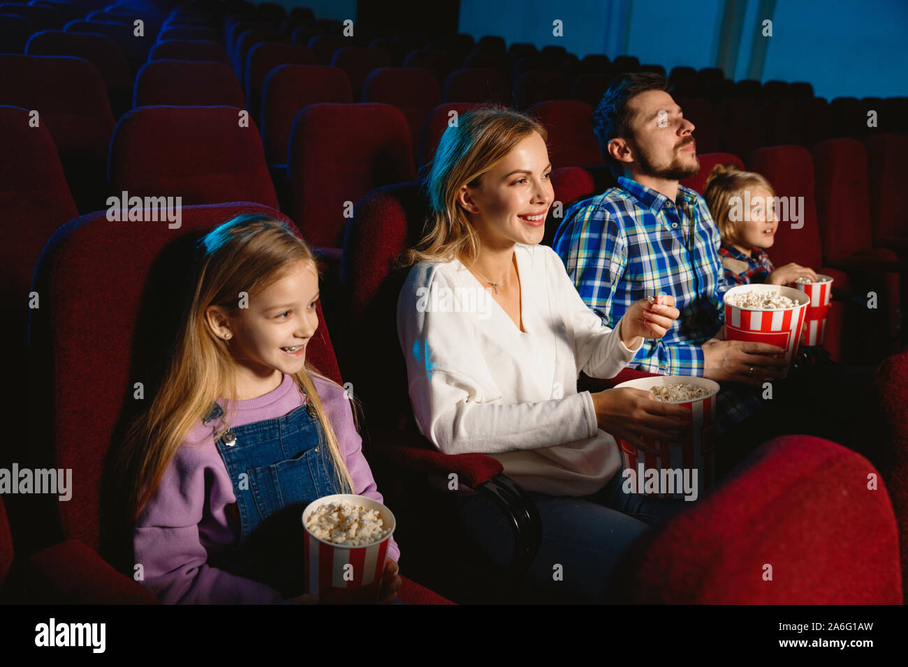 Young caucasian family watching a film at a movie theater, house or ...