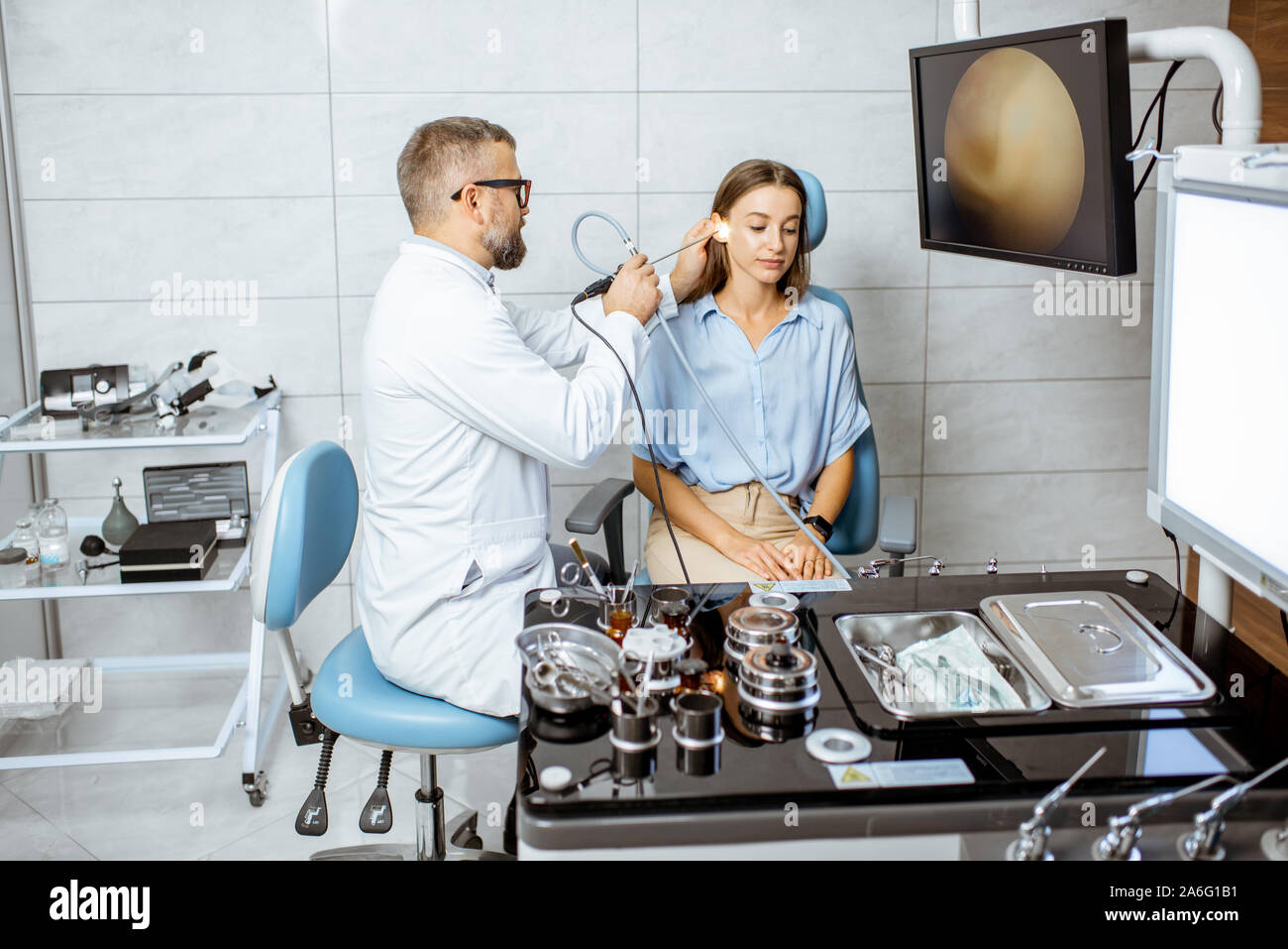 Senior otolaryngologist making endoscopic examination of an ear for a ...