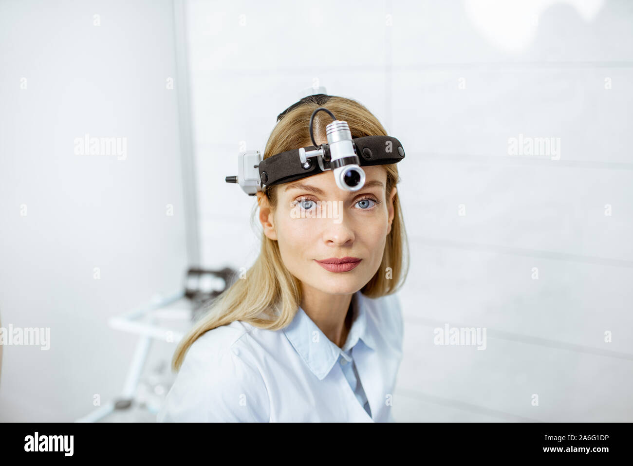 Portrait of a confident female otolaryngologist with headlight at the ...