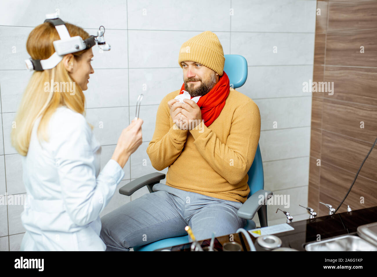 Adult patient catching cold, sitting in warm clothes with runny nose ...