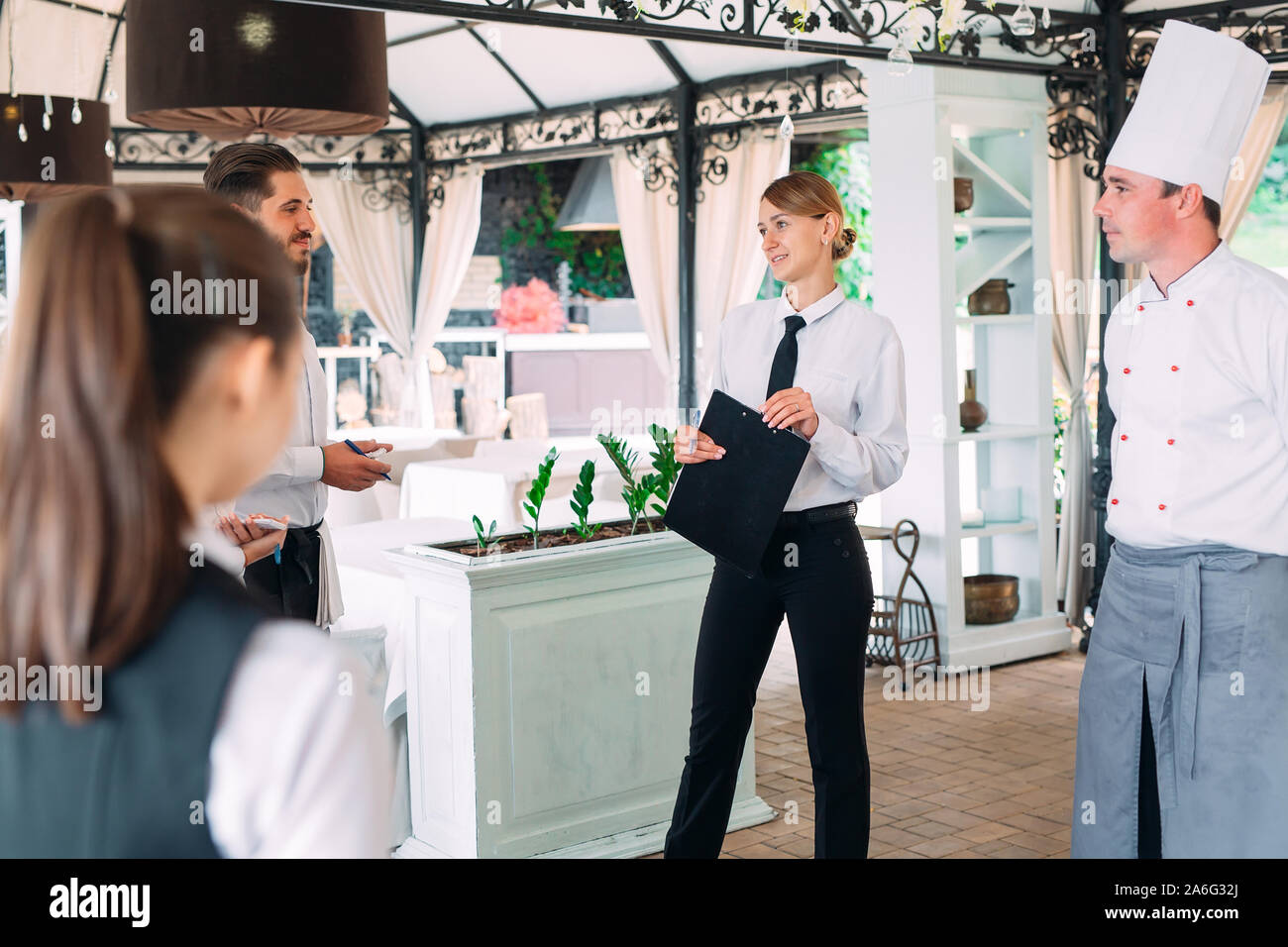 Restaurant manager and his staff in terrace. interacting to head chef ...