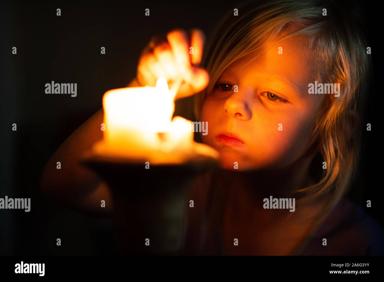 A cute, pretty little blonde girl lights a candle with a match after a ...