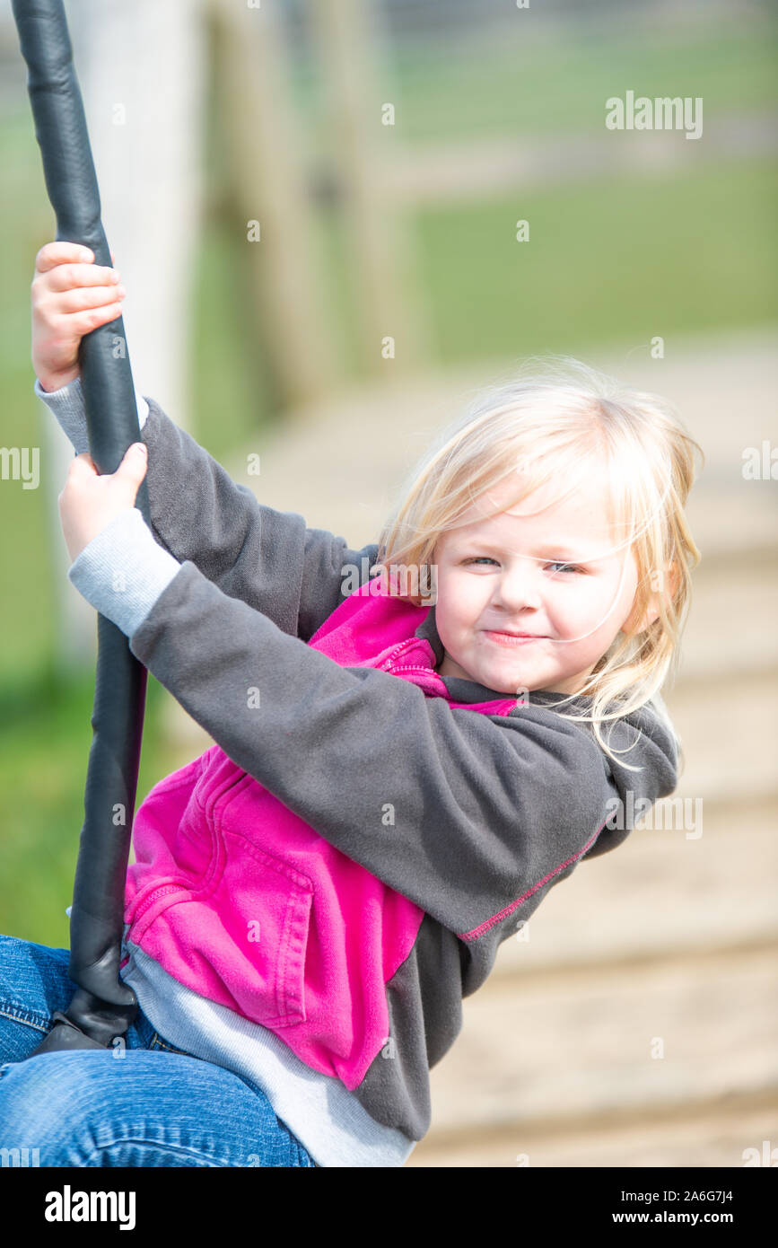 A pretty little girl playing at the park, climbing using the slide and swings enjoying being a ...